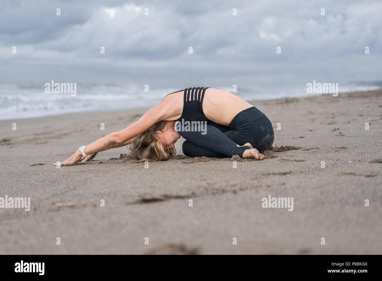 sporty young woman practicing yoga in Extended Child pose (Utthita ...