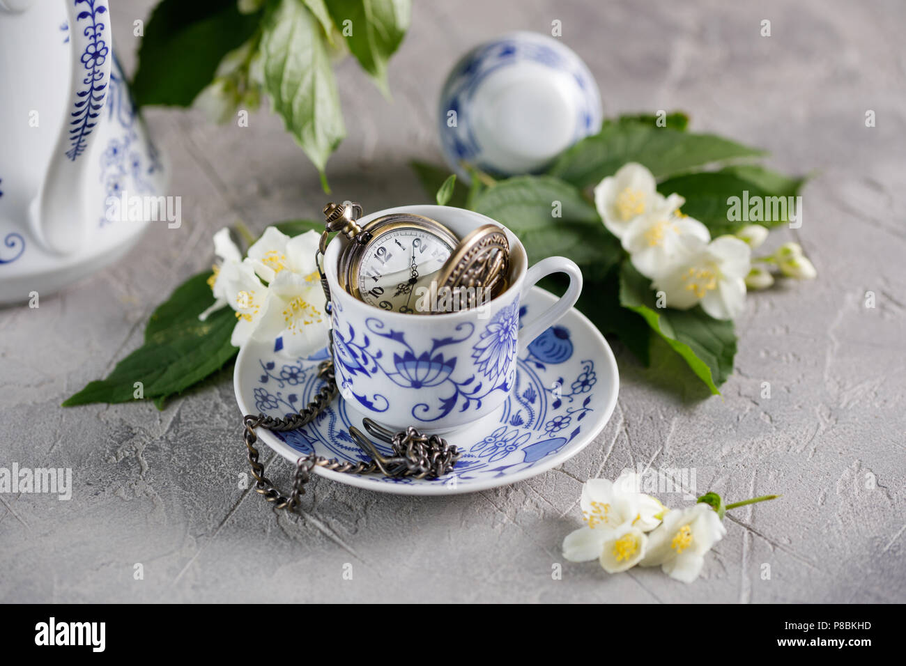 A gentle still-life with a tea set and jasmine flowers. A clock bulb in ...