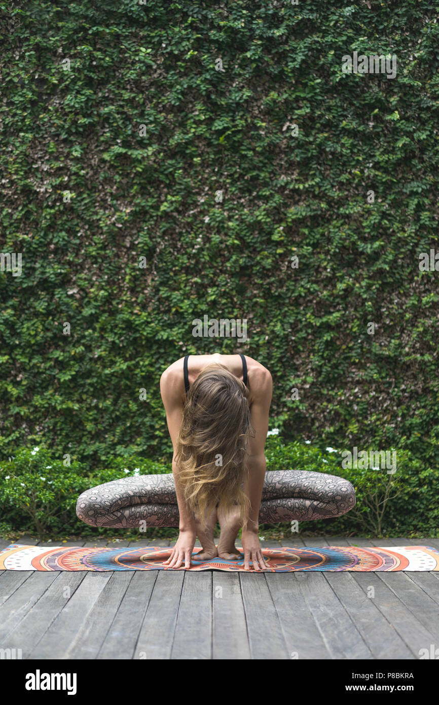 beautiful young woman practicing yoga in Squatting Toe Balance pose in ...