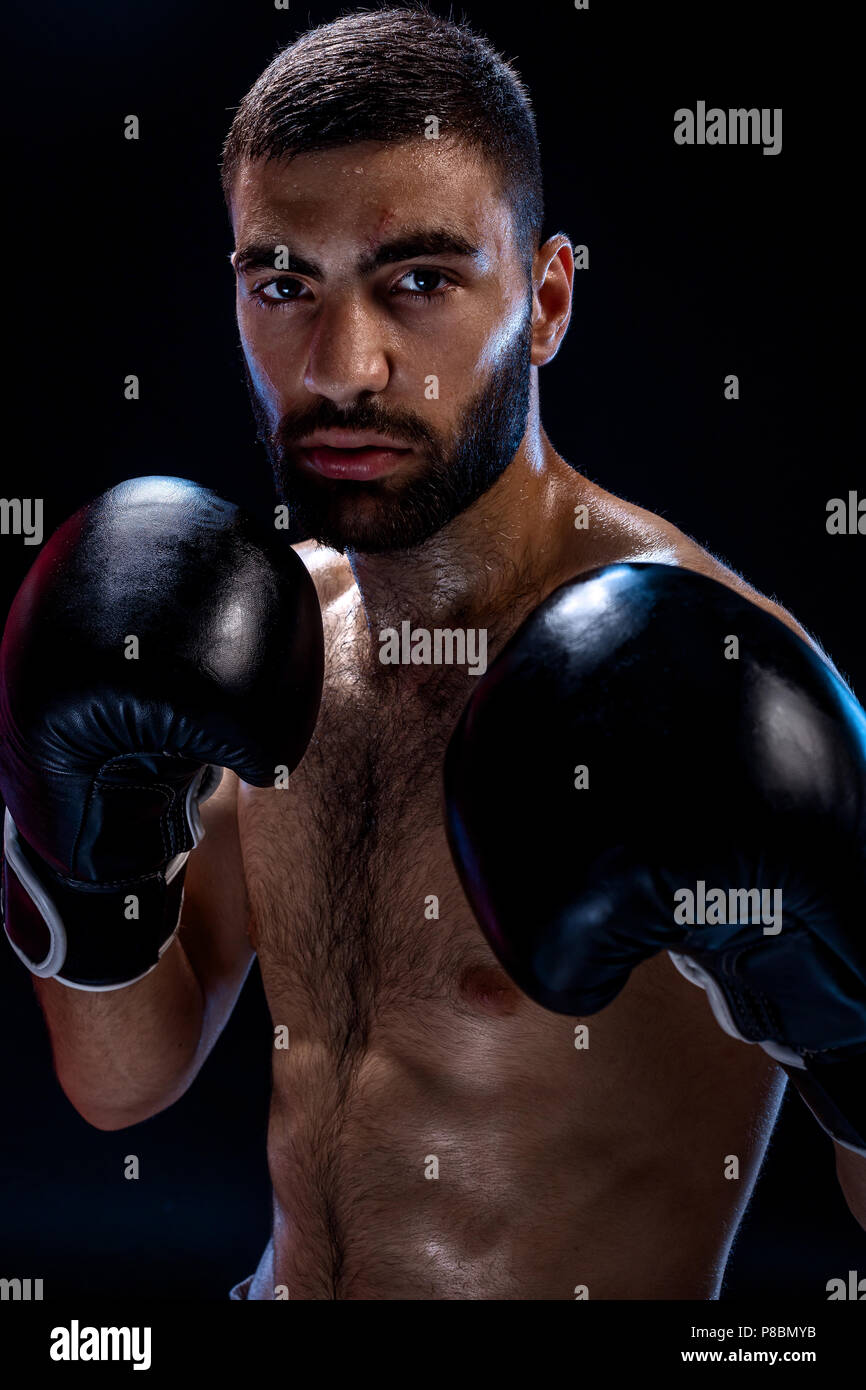 Strong muscular boxer in black boxing gloves. A man in a boxing stand ...