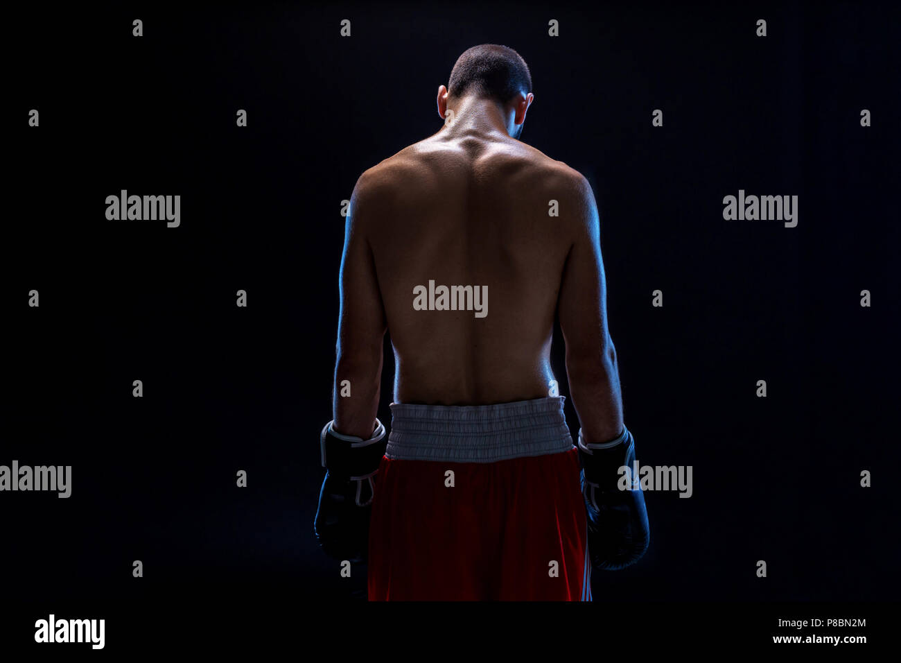 A boxer in his shorts stands with his back, his head is lowered ...