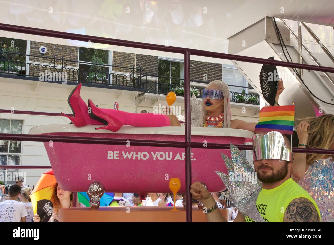 A drag queen in a pink bath tub that says "Be who you are" on the W ...