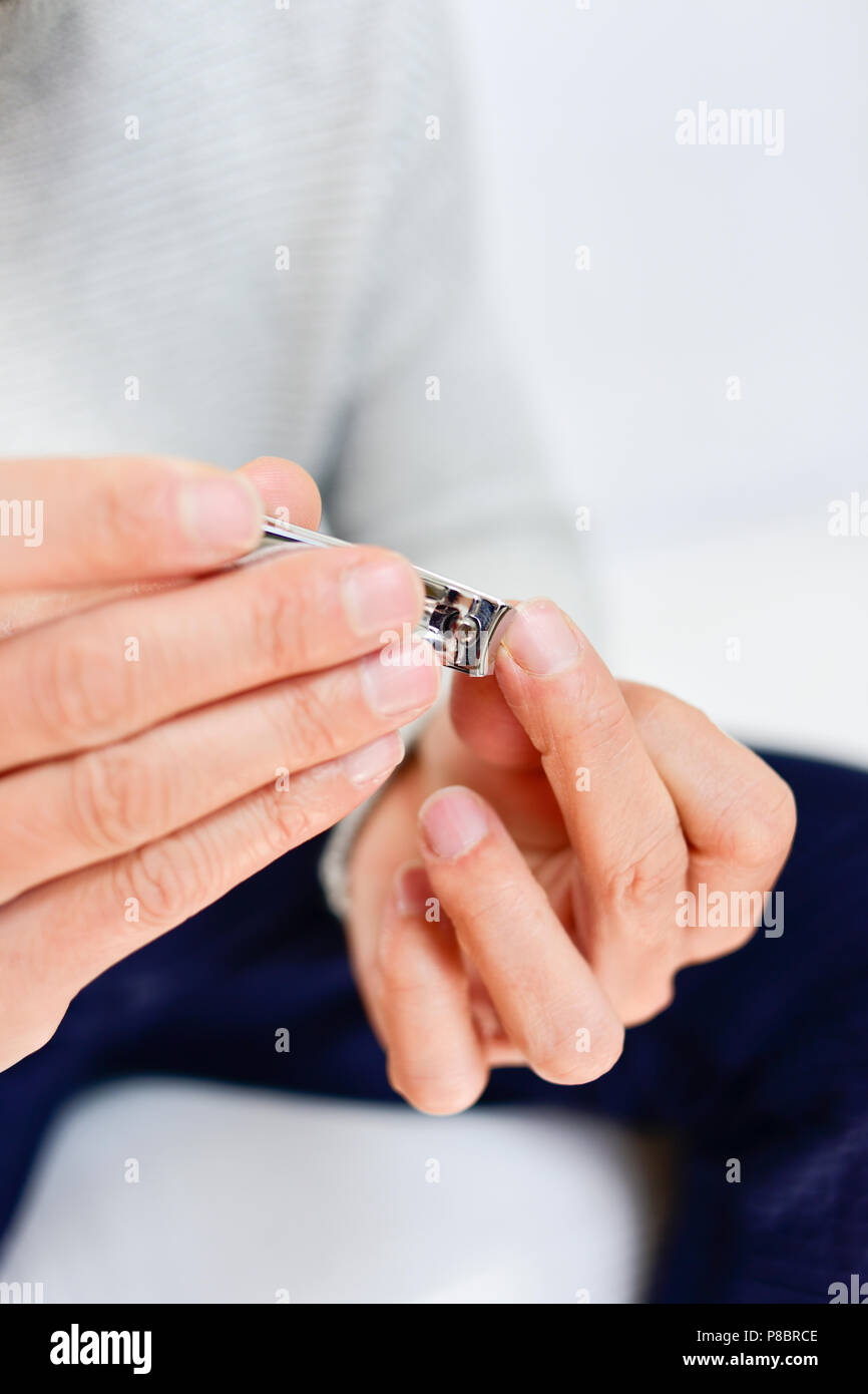 closeup of a young caucasian man cutting his fingernails with a nail ...
