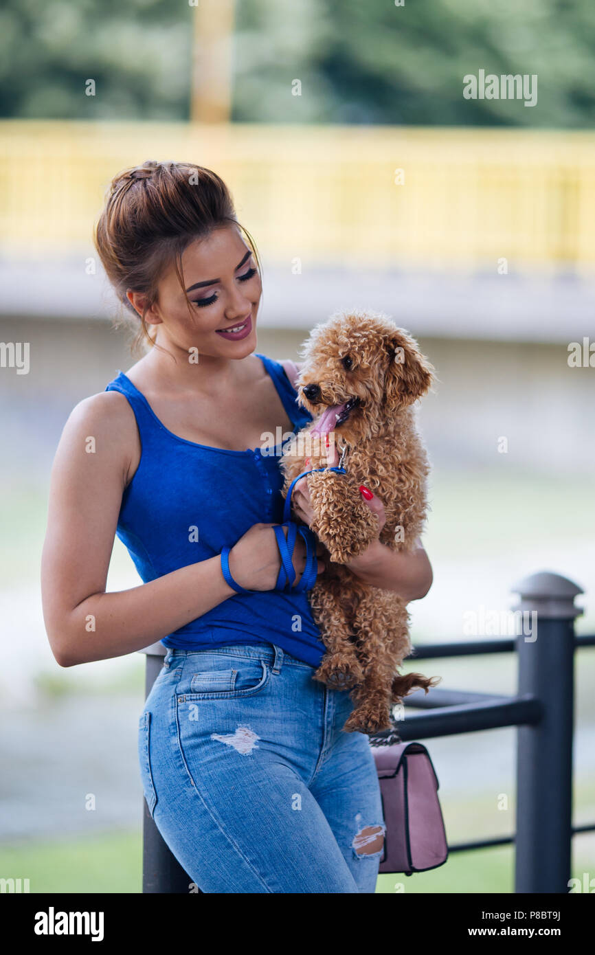 Portrait of beautiful smiling young woman with her little red poodle ...