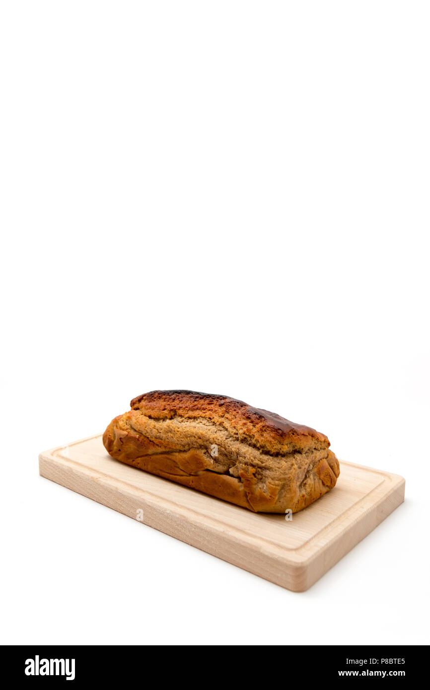 A homemade plumcake standing on a wooden board with a white background ...