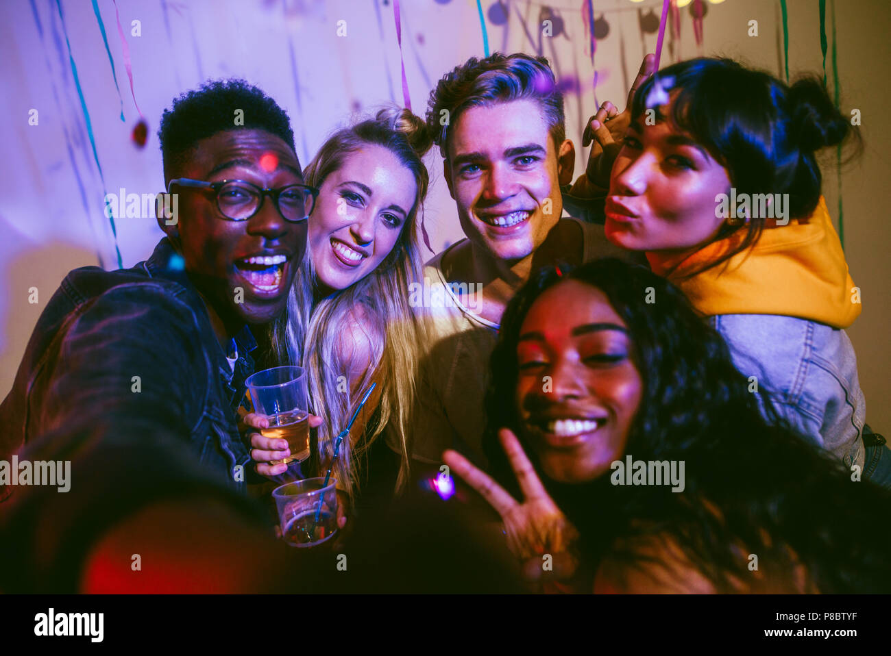 Friends Posing For A Selfie Holding Drinks And Showing Victory Signs At