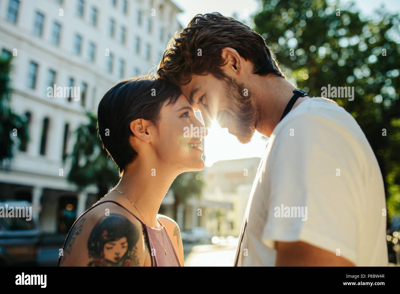 Man touching woman on forehead with his forehead standing on the street ...