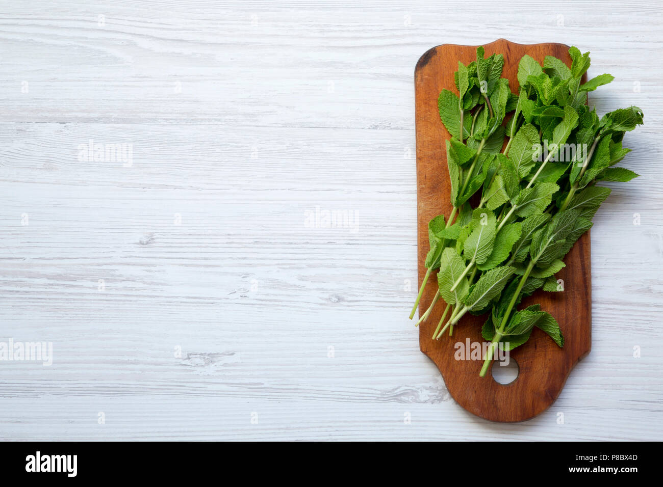 Top view, fresh mint on wooden board over white wooden background. Copy ...