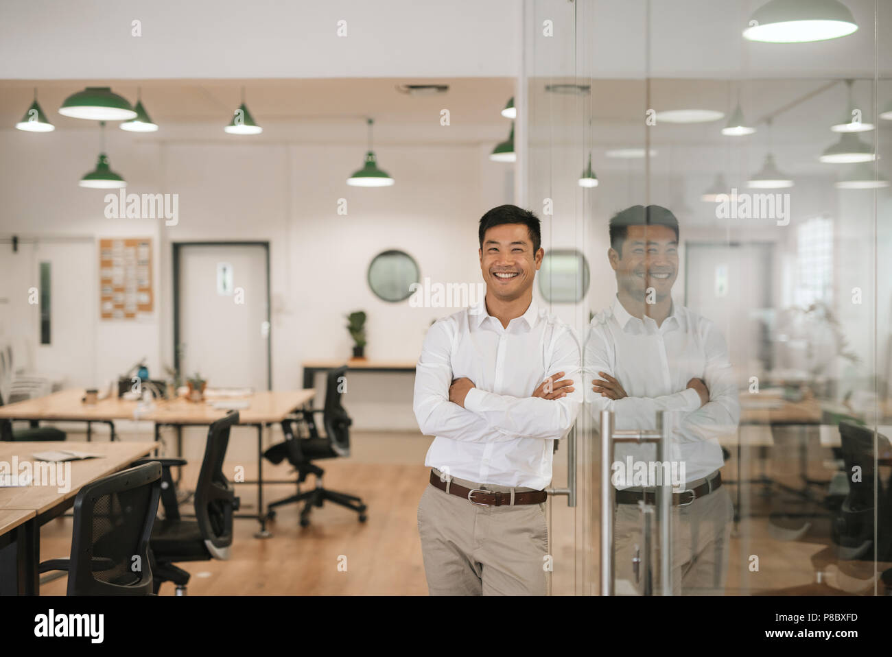 Confident businessman leaning against glass wall hi-res stock ...