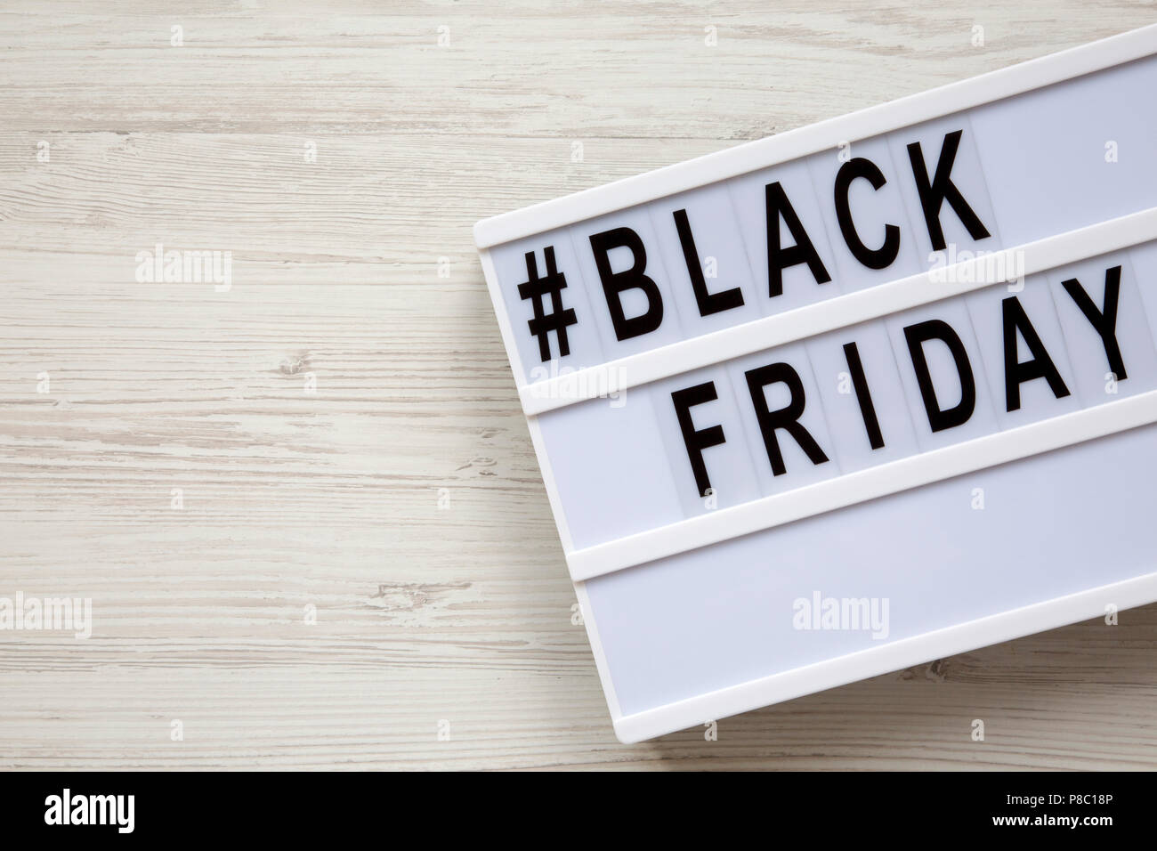 Black friday word on lightbox over white wooden surface, top view. Copy ...