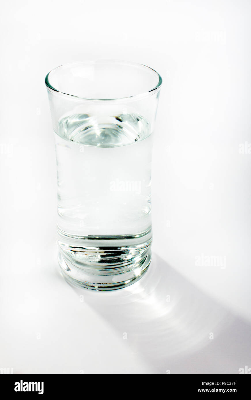 A single glass of water against a light gray background. Shadow commnig ...