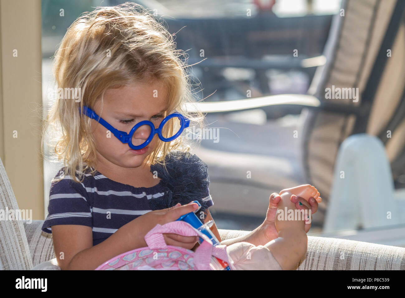 Preteen girl, profile, blonde, playing doctor on doll. looking down ...