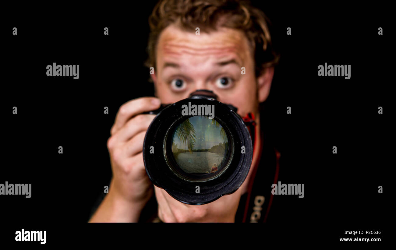 A professional photographer holds his camera close to his face Stock ...