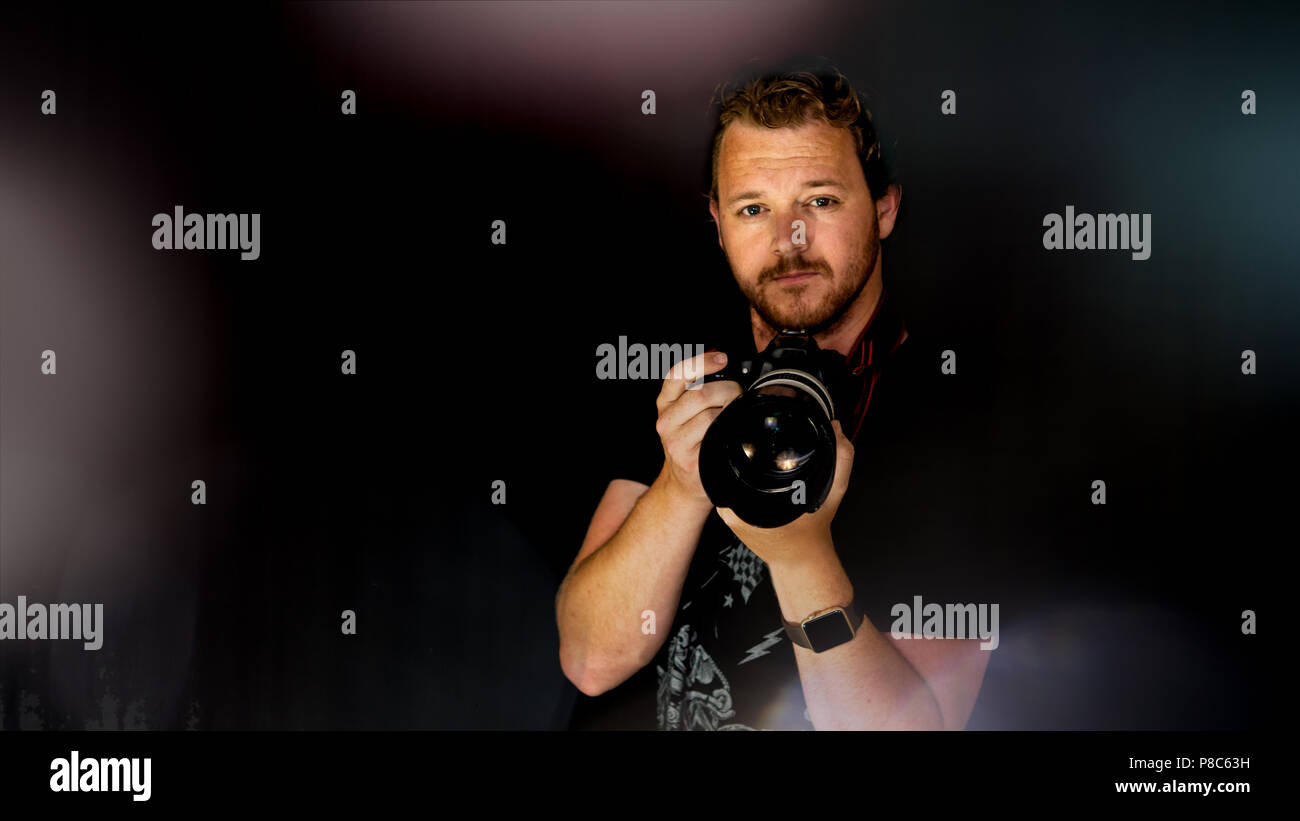 A professional photographer holds his camera close to his face Stock ...