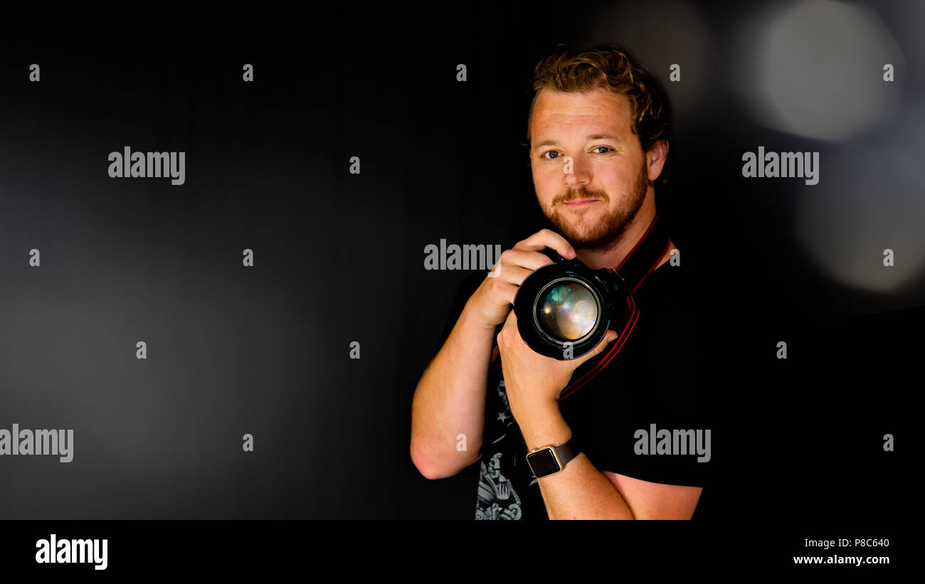 A professional photographer holds his camera close to his face Stock ...