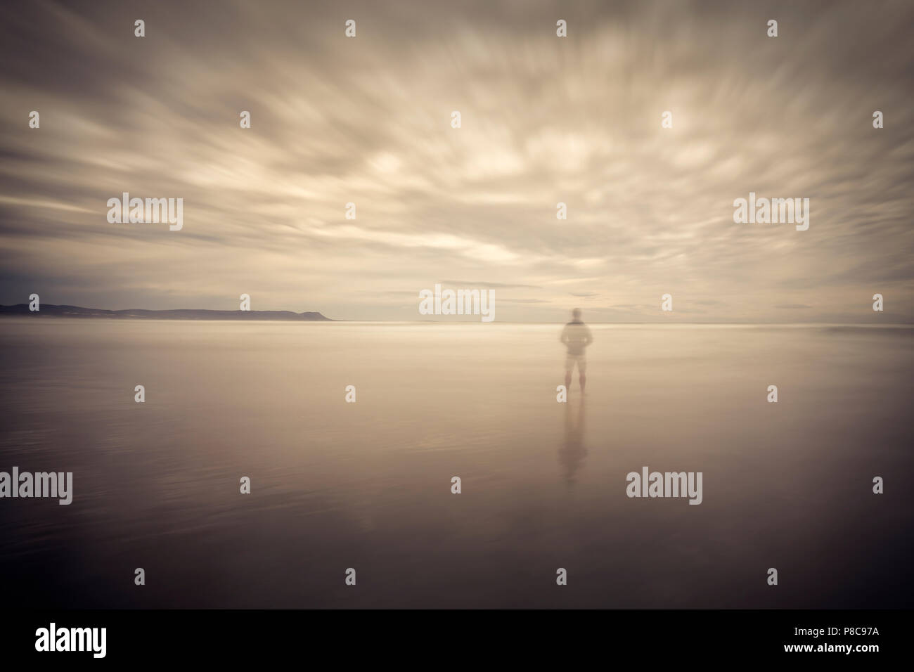 A man standing at the beach watching the sunrise hi-res stock ...