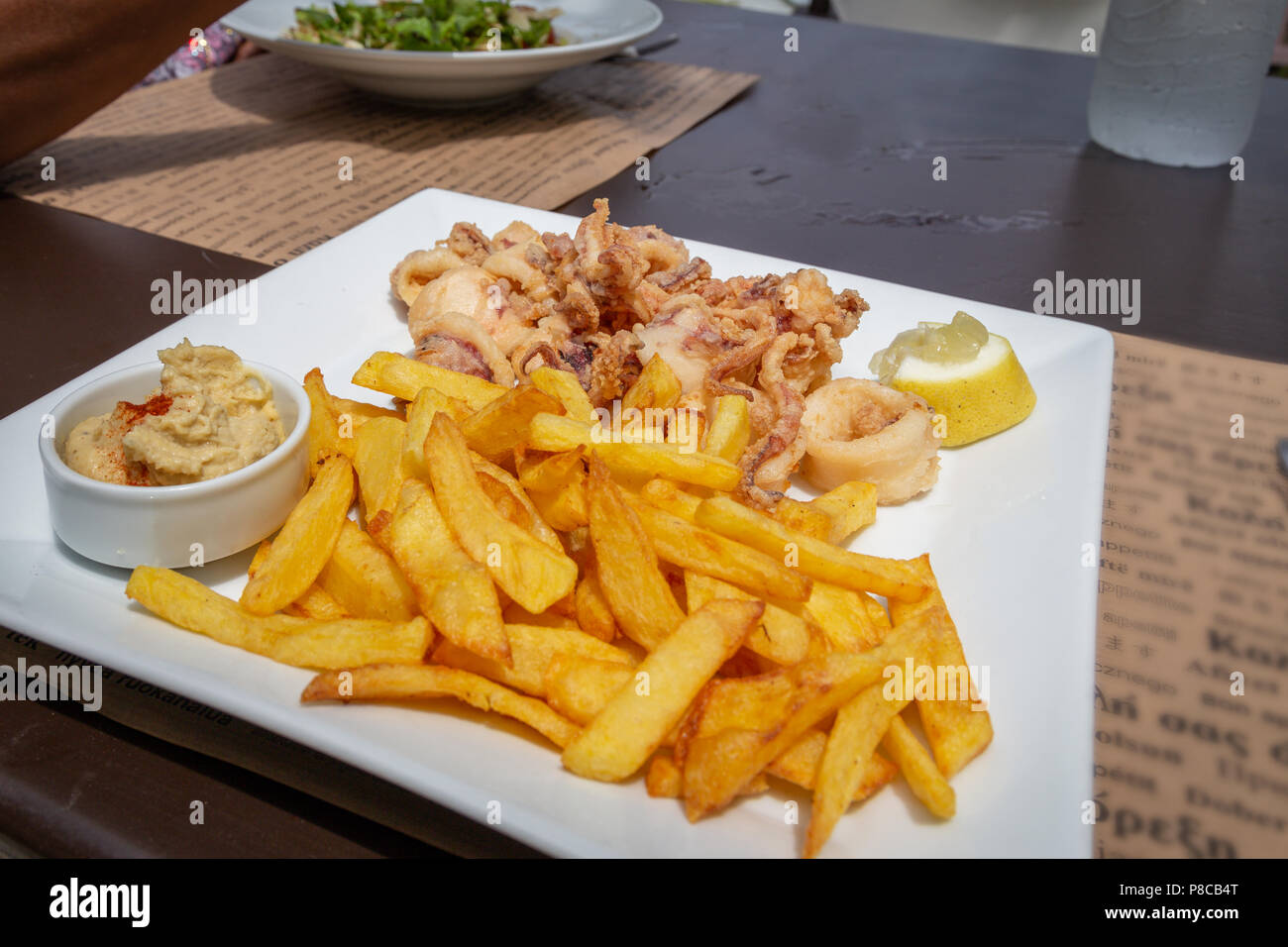 A plate of fried calamari and chips with a pot of hummus Stock Photo ...