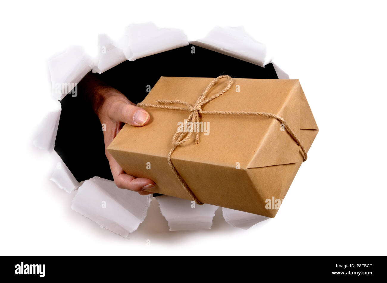 Man hand delivering or giving parcel through torn white paper ...
