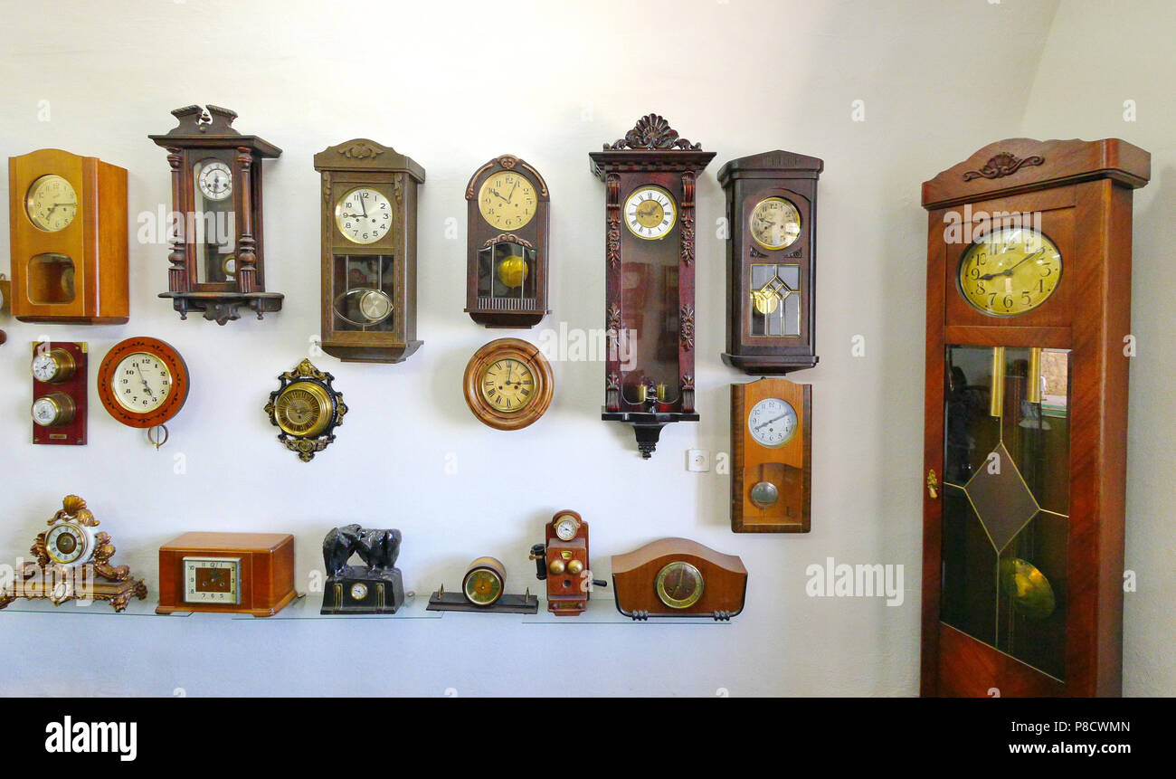 Museum exhibition with a lot of different wooden clock on the wall ...