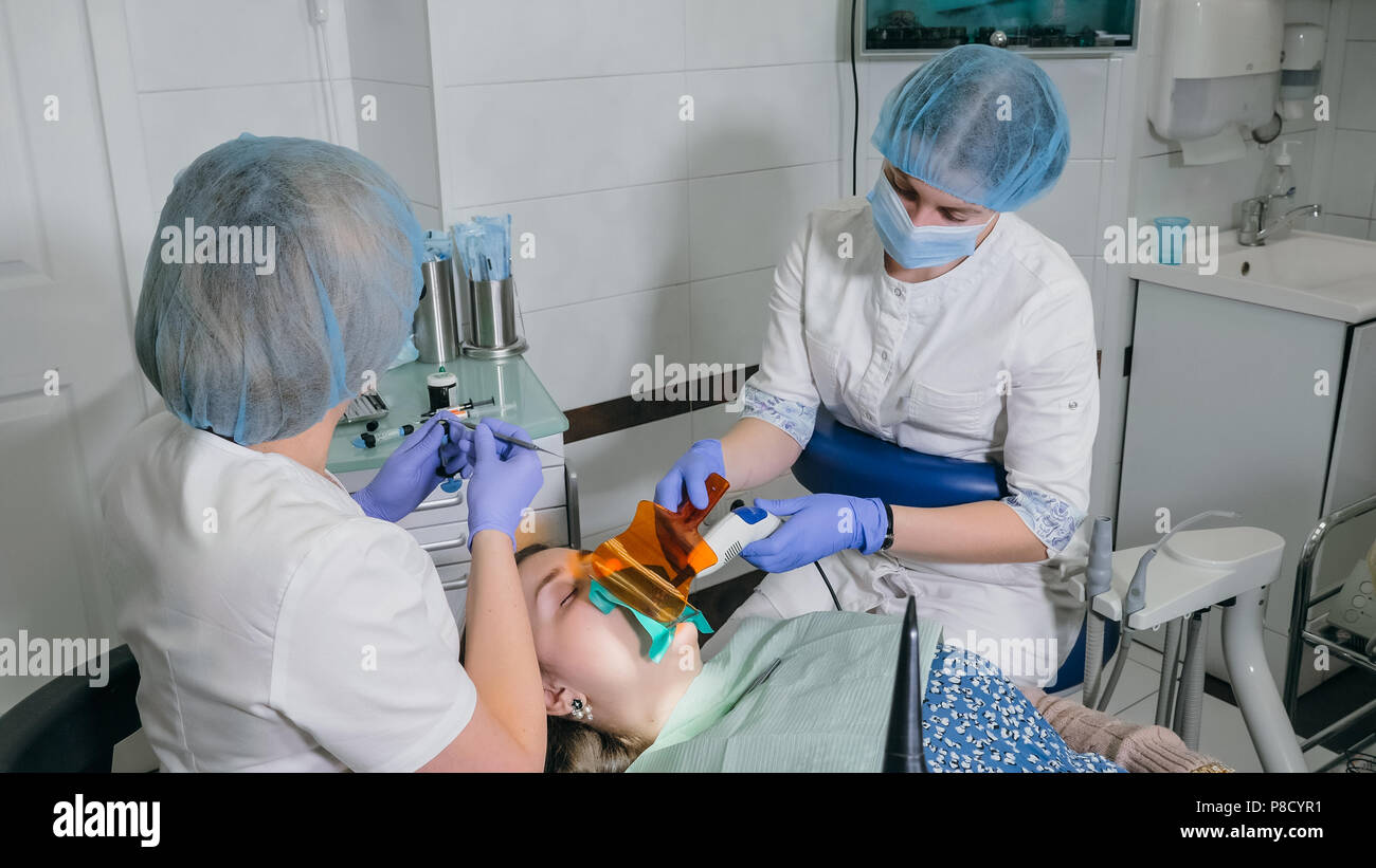 Woman at dentist clinic gets dental treatment to fill a cavity in a ...