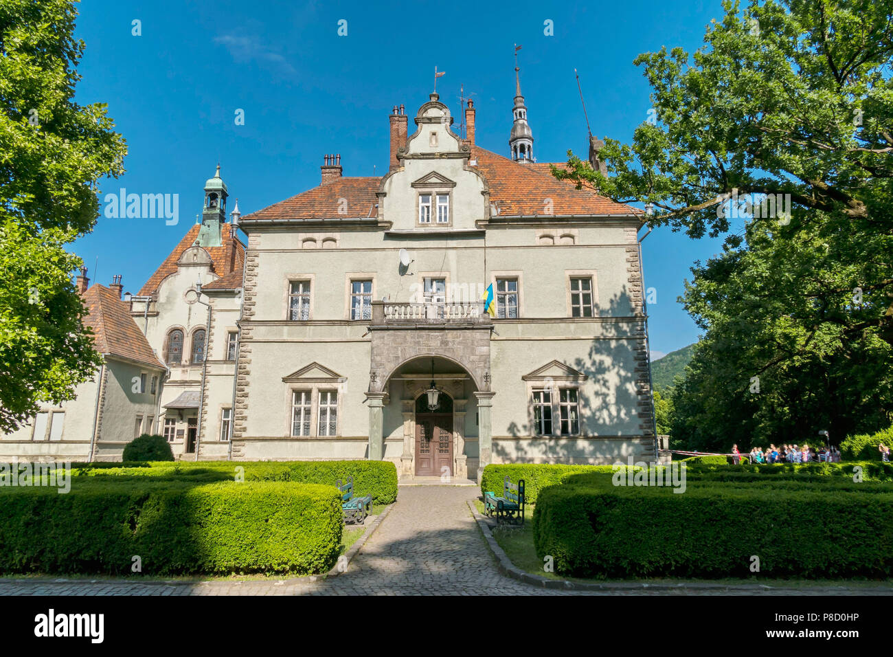 An ancient manor house with a roof from a once red tile. Near it grow ...