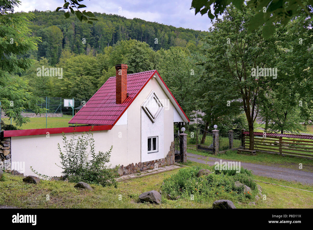 A small house with a tiled roof and a brick pipe located next to the ...