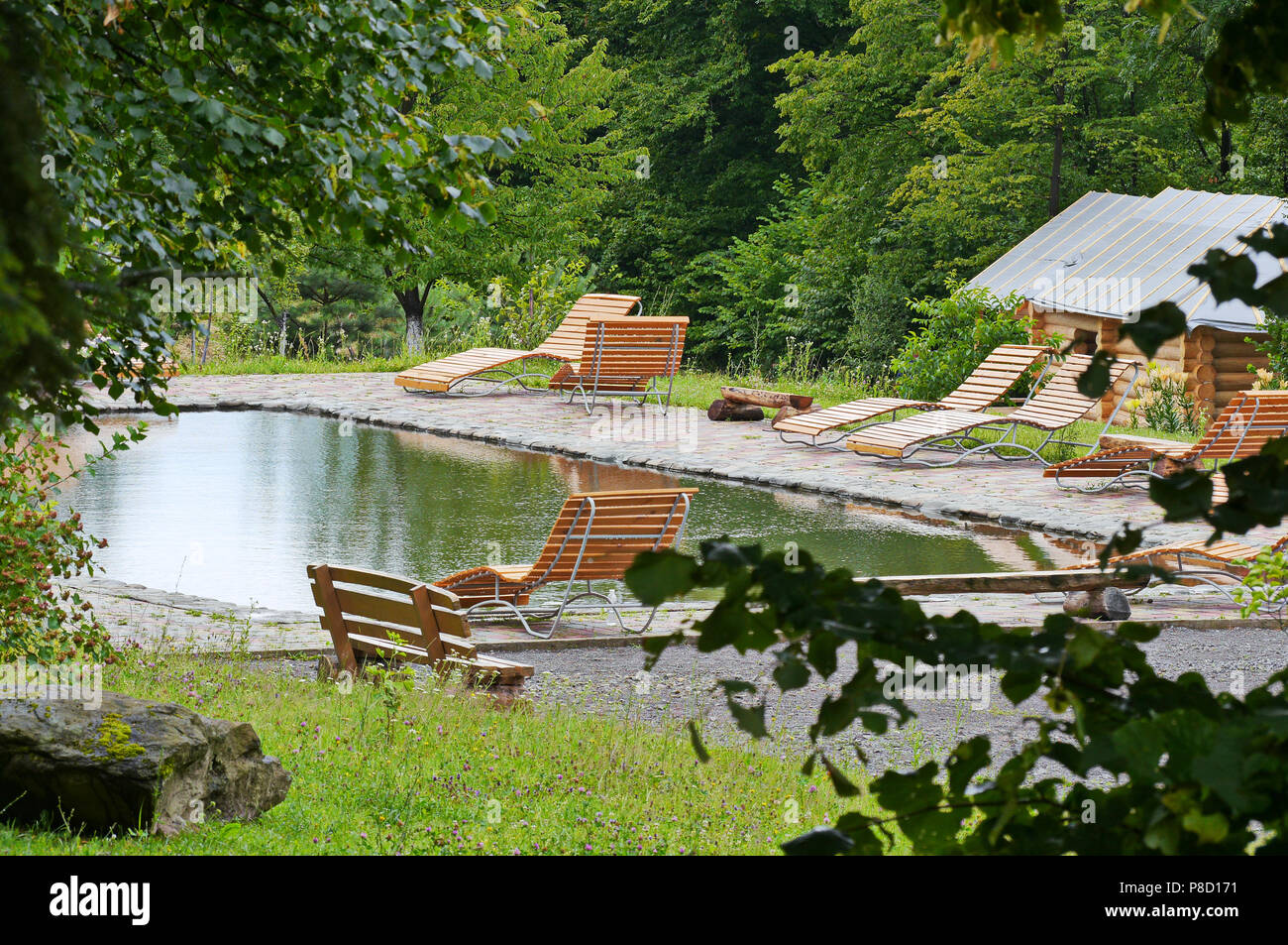 A picturesque swimming pool with wooden sun loungers on the sides in ...