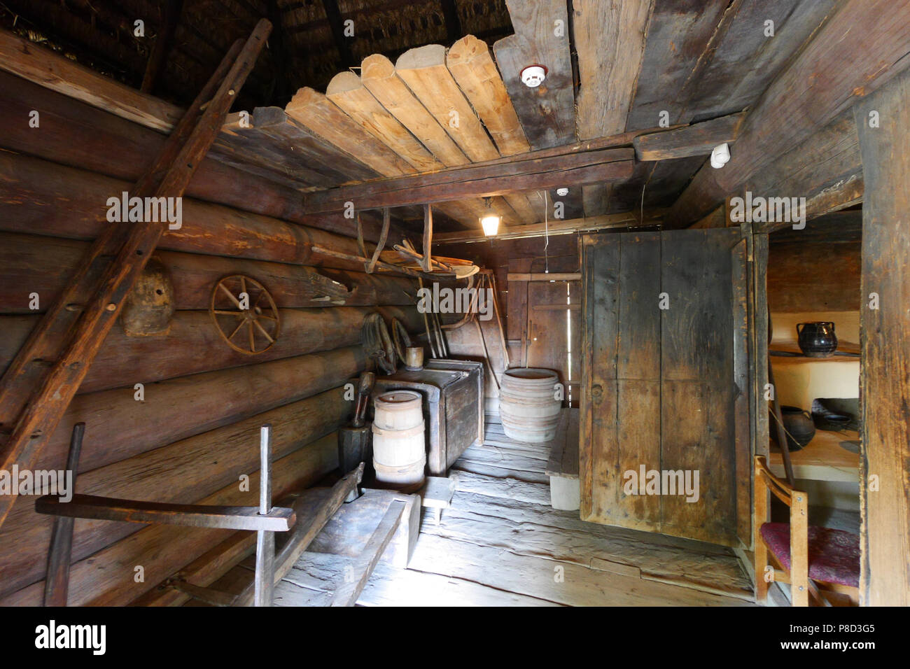 Entrance hall in a wooden hut with a staircase and wheel on the wall ...