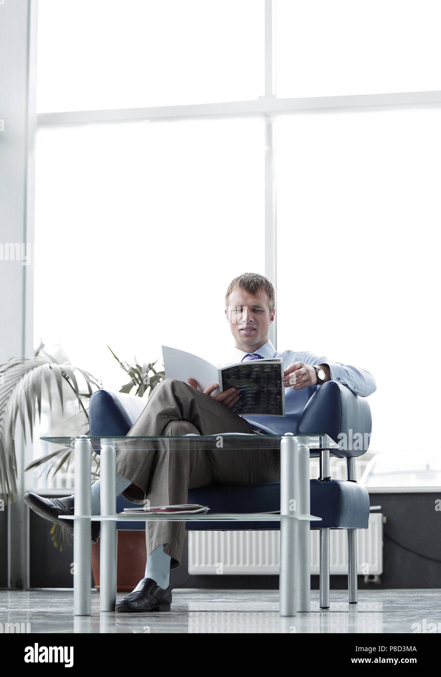 Businessman reading magazine in waiting room Stock Photo - Alamy