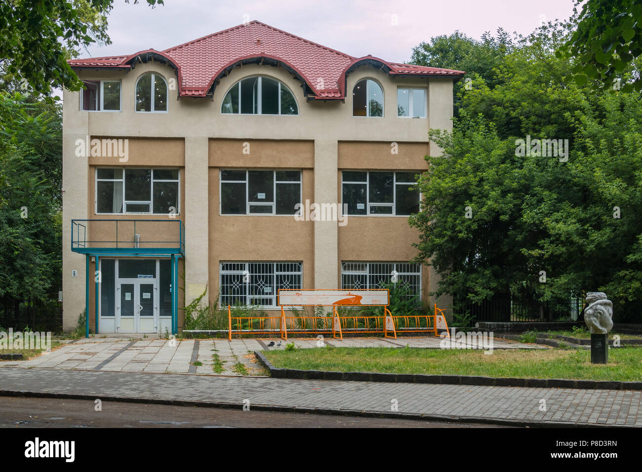 Three-storey coffee building with a red roof. Around it trees and a ...