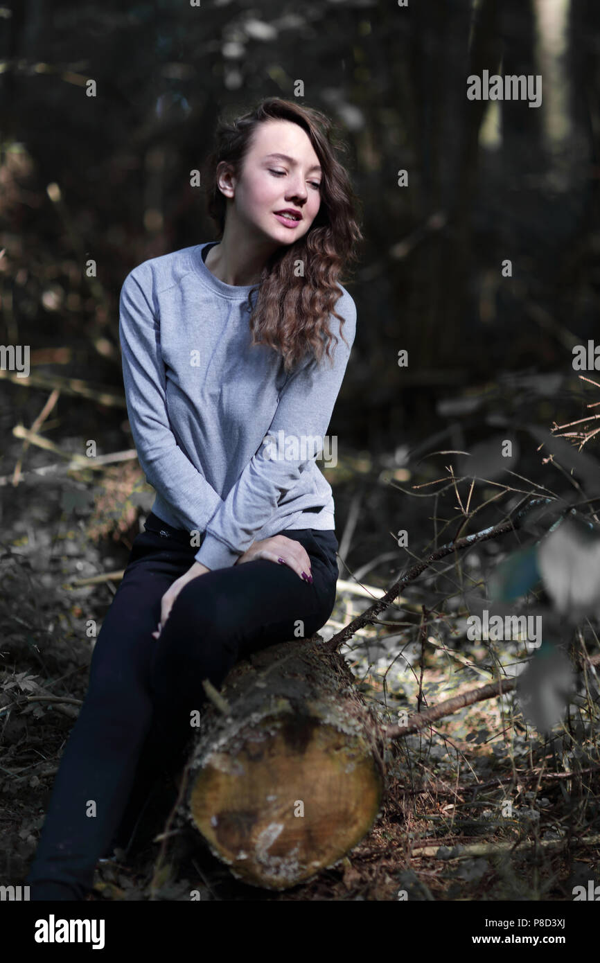 beautiful young woman sitting on a log Stock Photo - Alamy