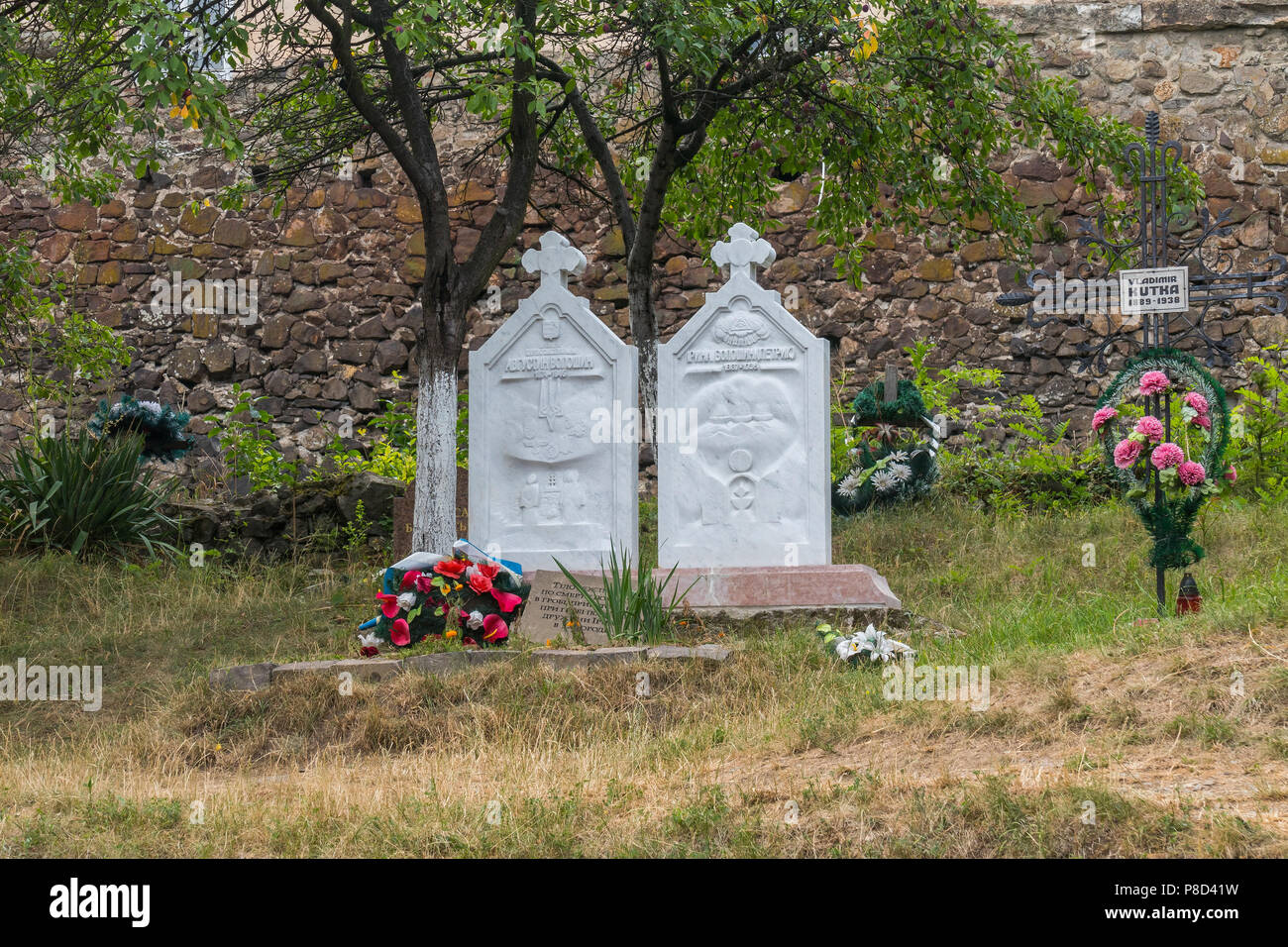Memorial monuments on the background of tall trees and an ancient stone ...