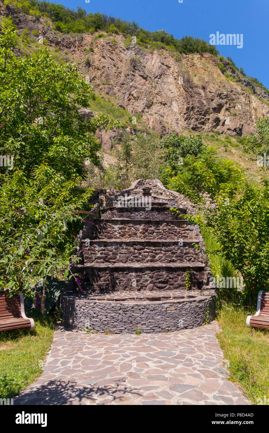 A cascade of waterfall covered with stone at the foot of the rock and ...
