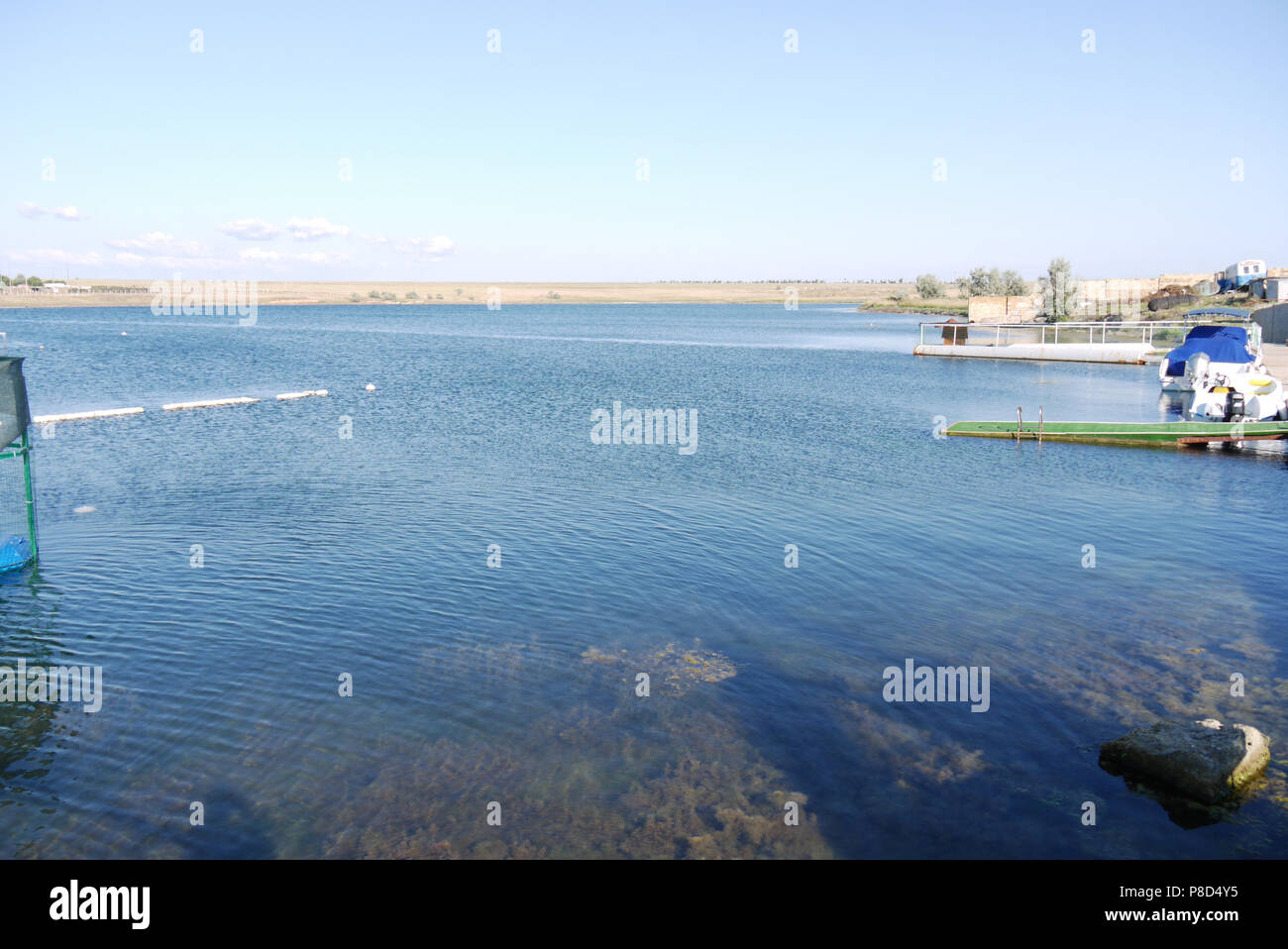 transparent clear water of a blue lake with piers along the shore . For ...