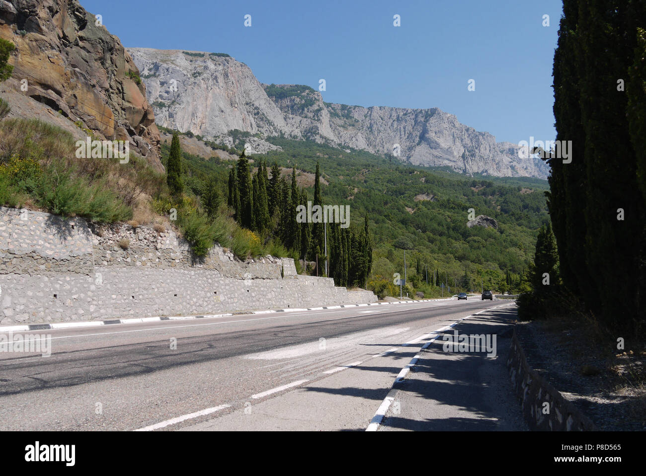 A large motorway on the background of high rocky mountains and green ...
