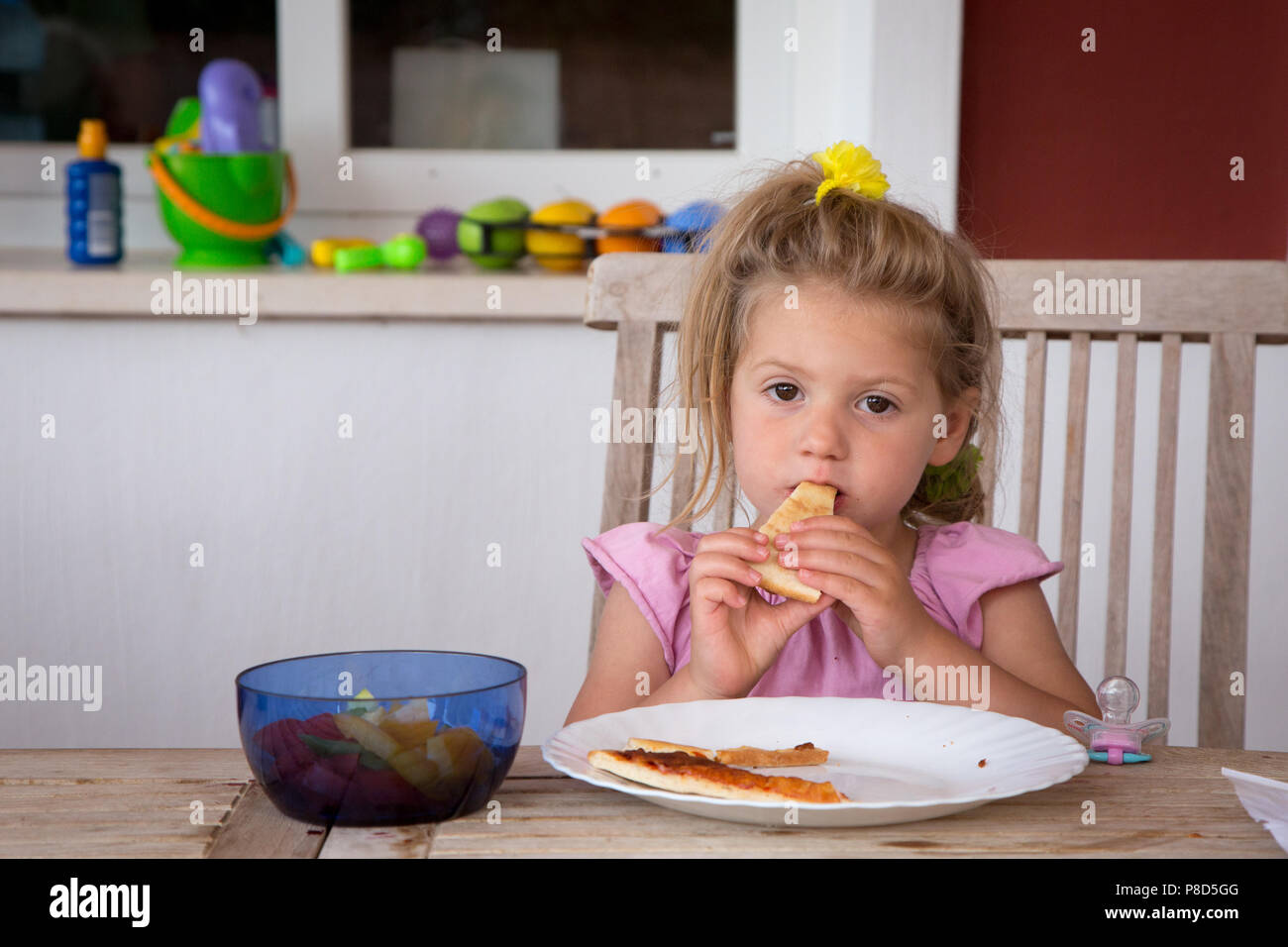 Girl of 2 and a half eating a slice of pizza outdoors at home Stock ...