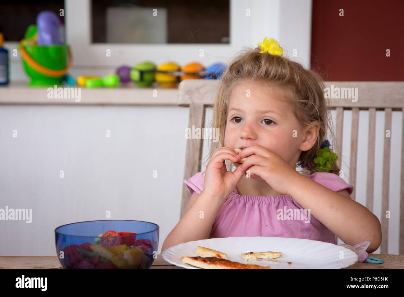 Girl of 2 and a half eating a slice of pizza outdoors at home Stock ...