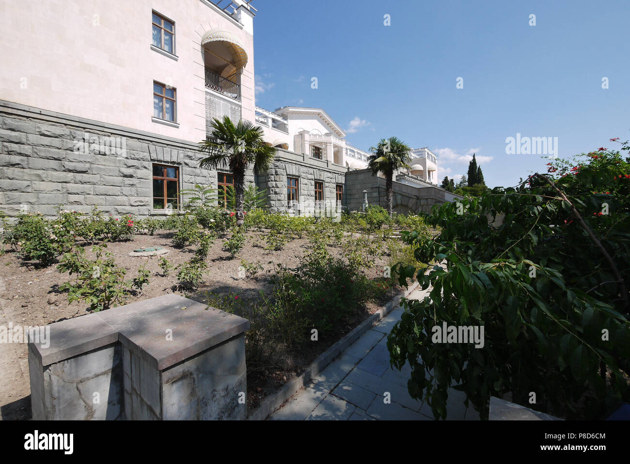 palm trees growing among flowers in a flower bed next to a building of ...