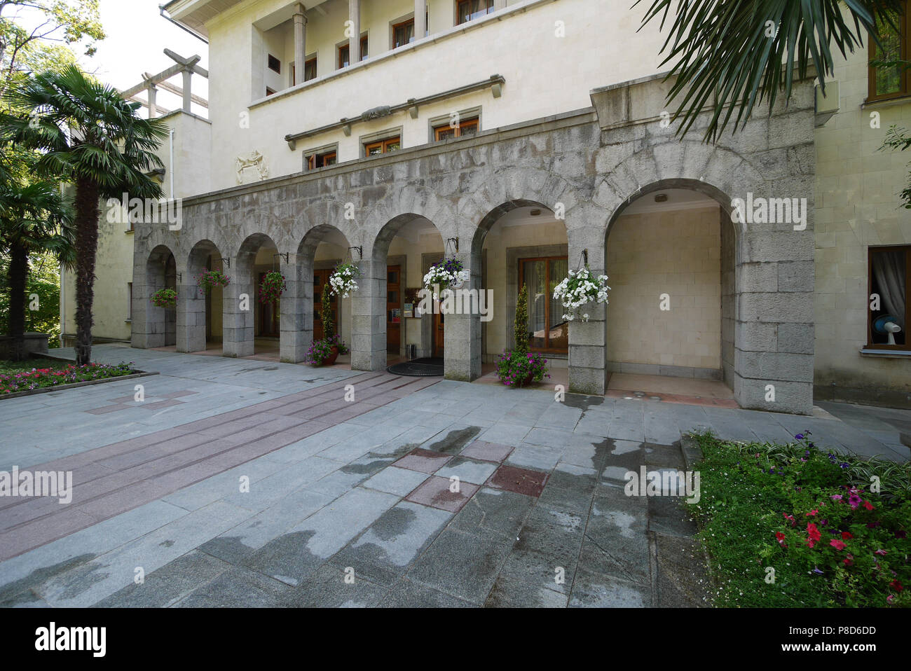 Beautiful building of a sanatorium complex with wide gray stobas, palms ...