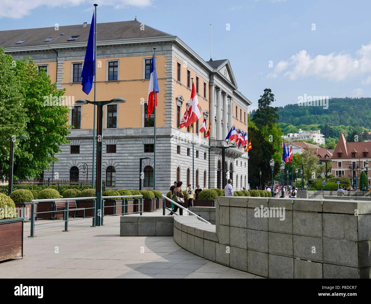People walking past the French Mairie, City Hall, with various flags ...
