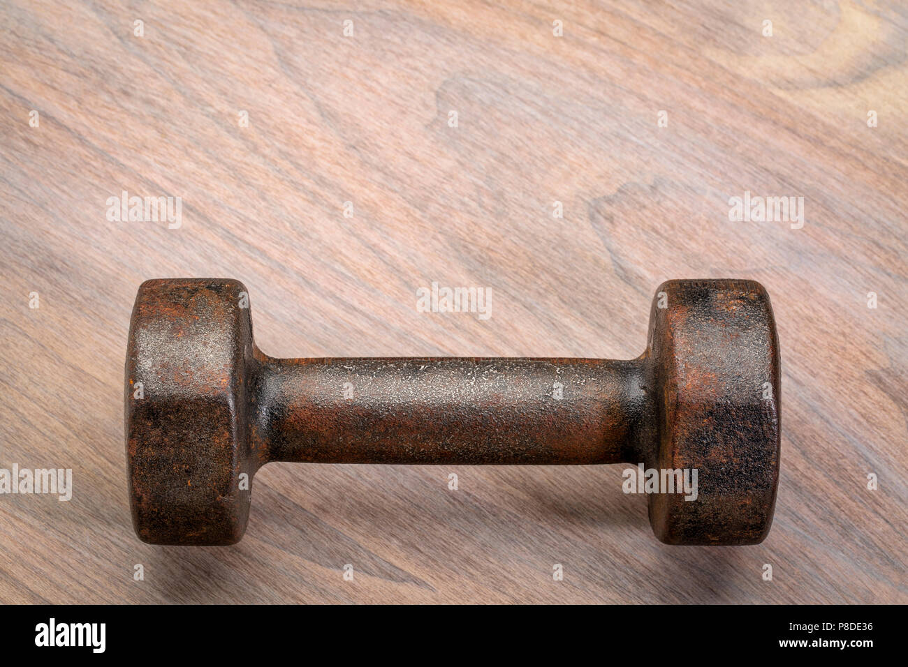 vintage rusty iron dumbbell on grained wood background - fitness ...