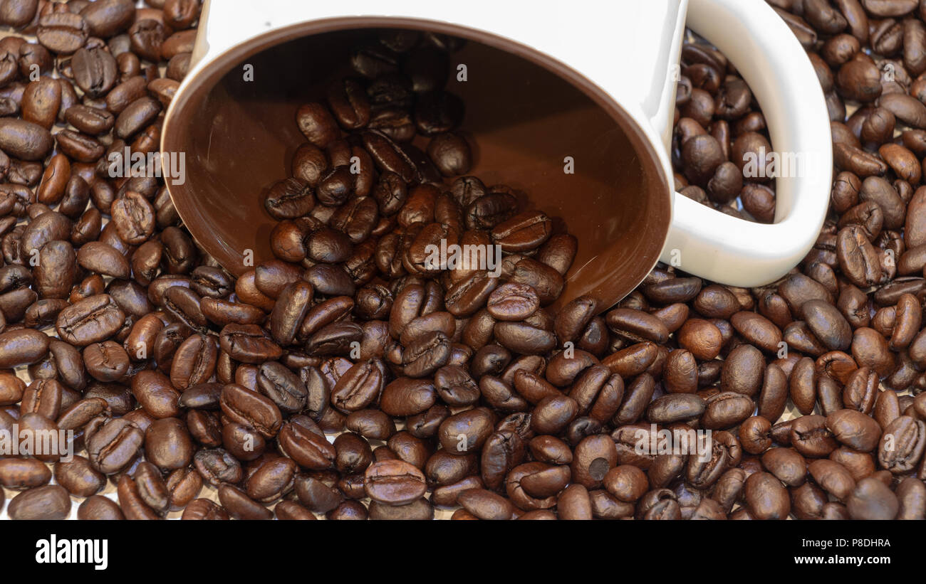 Coffee beans spilling out of a white coffee cup Stock Photo - Alamy