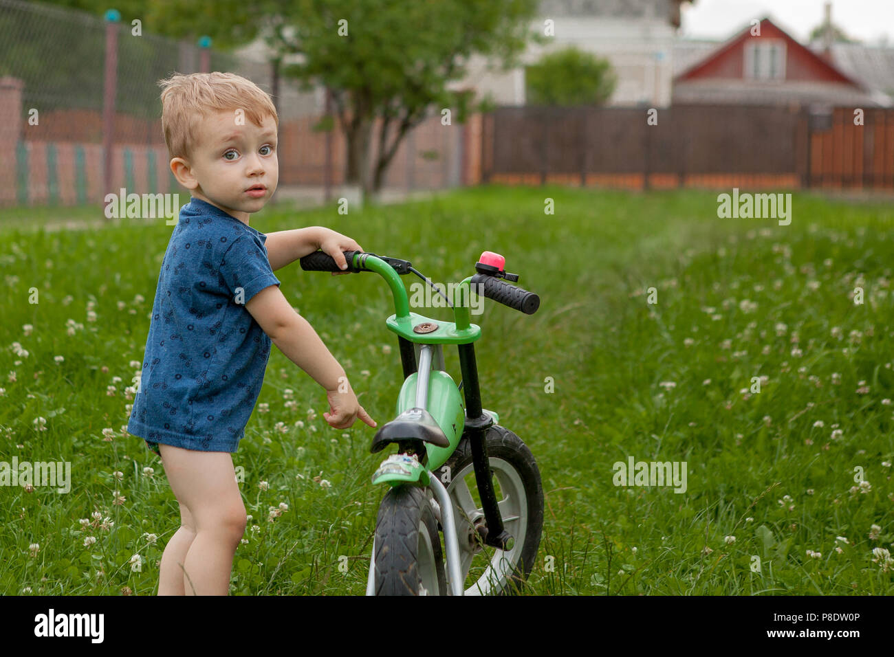 A cute little boy with a bicycle near the house, a sport for children ...