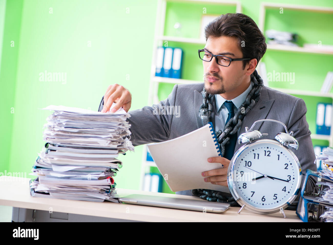 Employee chained to his desk due to workload Stock Photo - Alamy