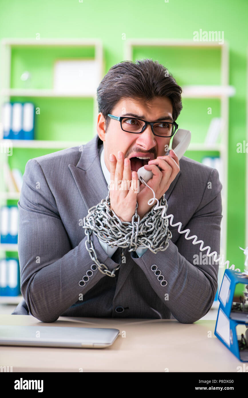 Employee chained to his desk due to workload Stock Photo - Alamy