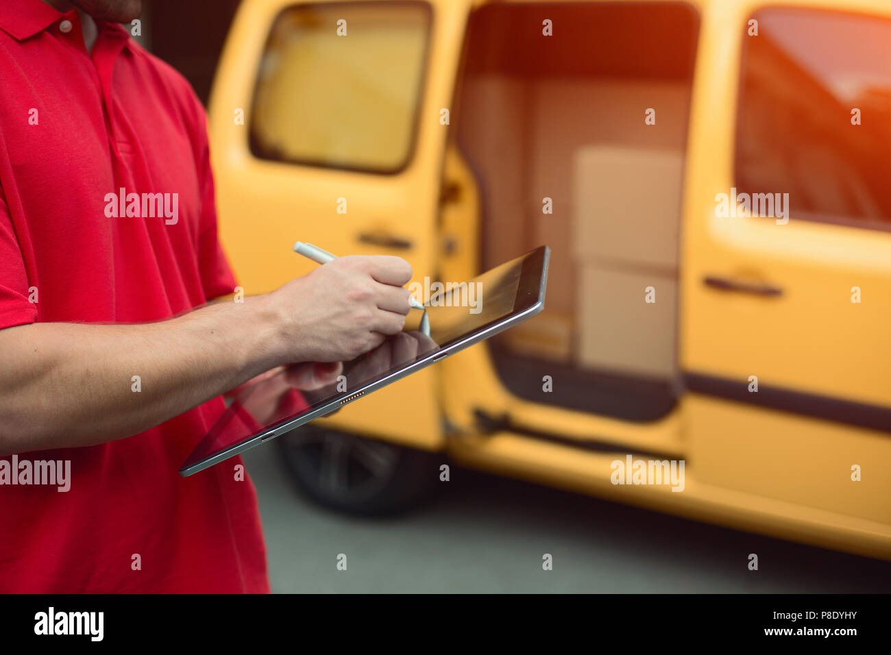 Delivery man signing digital tablet Stock Photo - Alamy