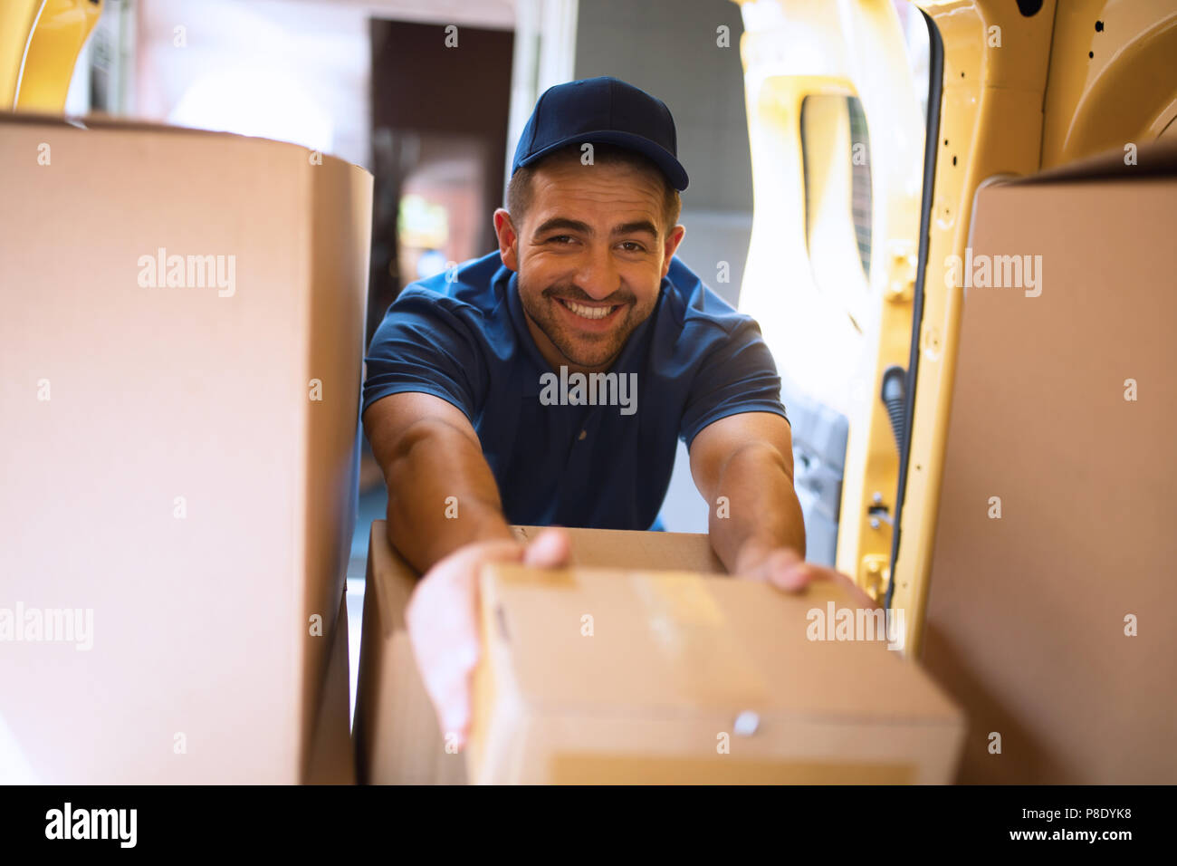 Delivery guy taking boxes out of van Stock Photo - Alamy