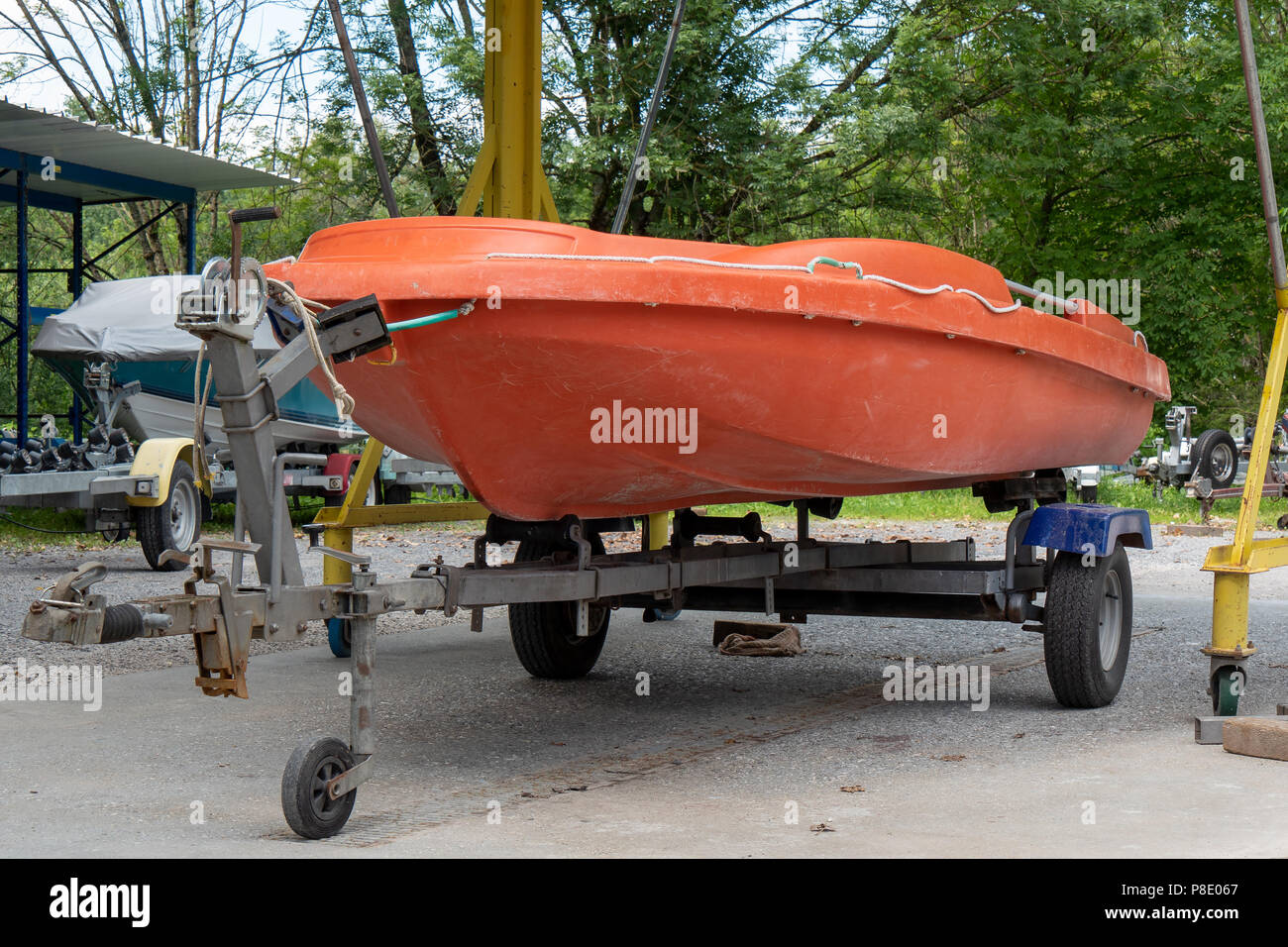 an orange color motor boats on trailer in parking Stock Photo - Alamy