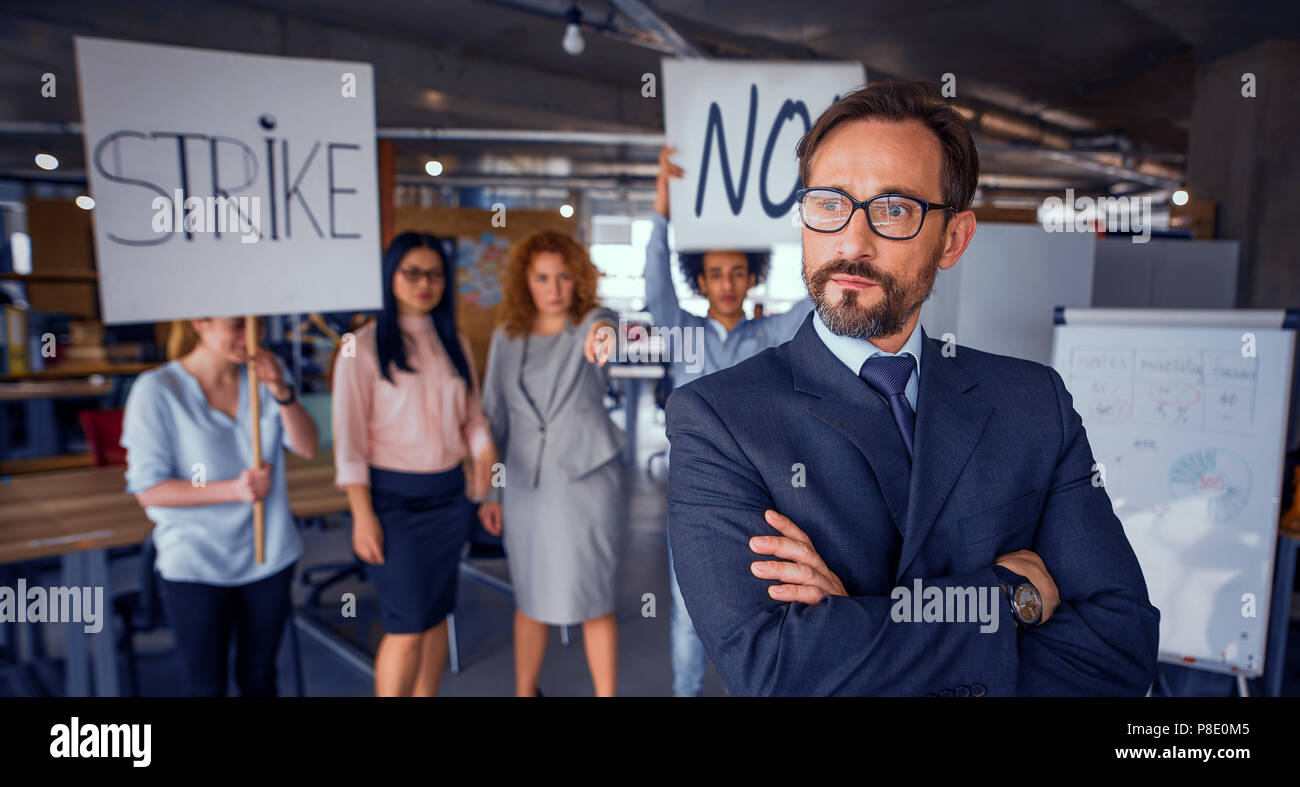 Unsatisfied employees on strike in the office, director standing with ...