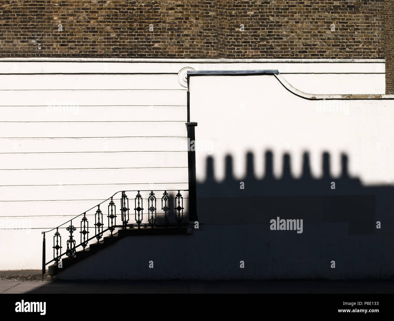 White plaster wall, brick wall and steps with iron decorative handrail ...